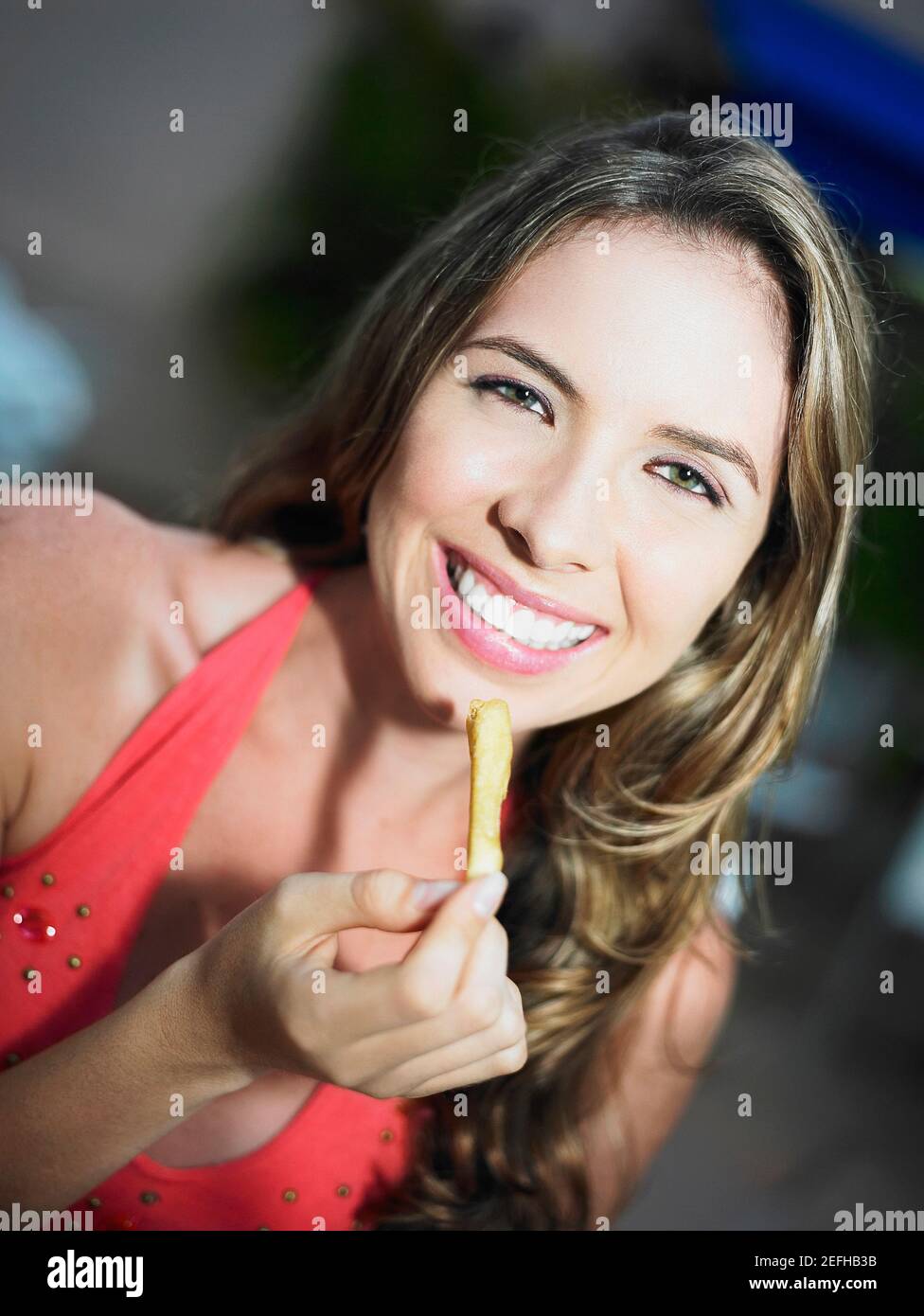 Portrait of a young woman eating French fries Stock Photo - Alamy