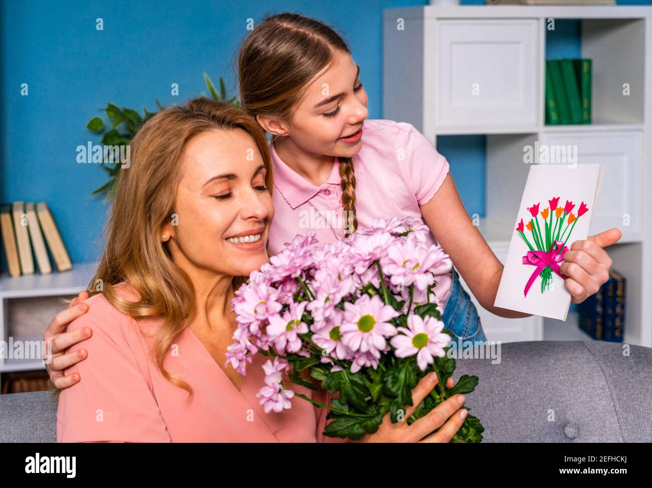 Female child presenting flowers to her mom at home, happy domestic life ...