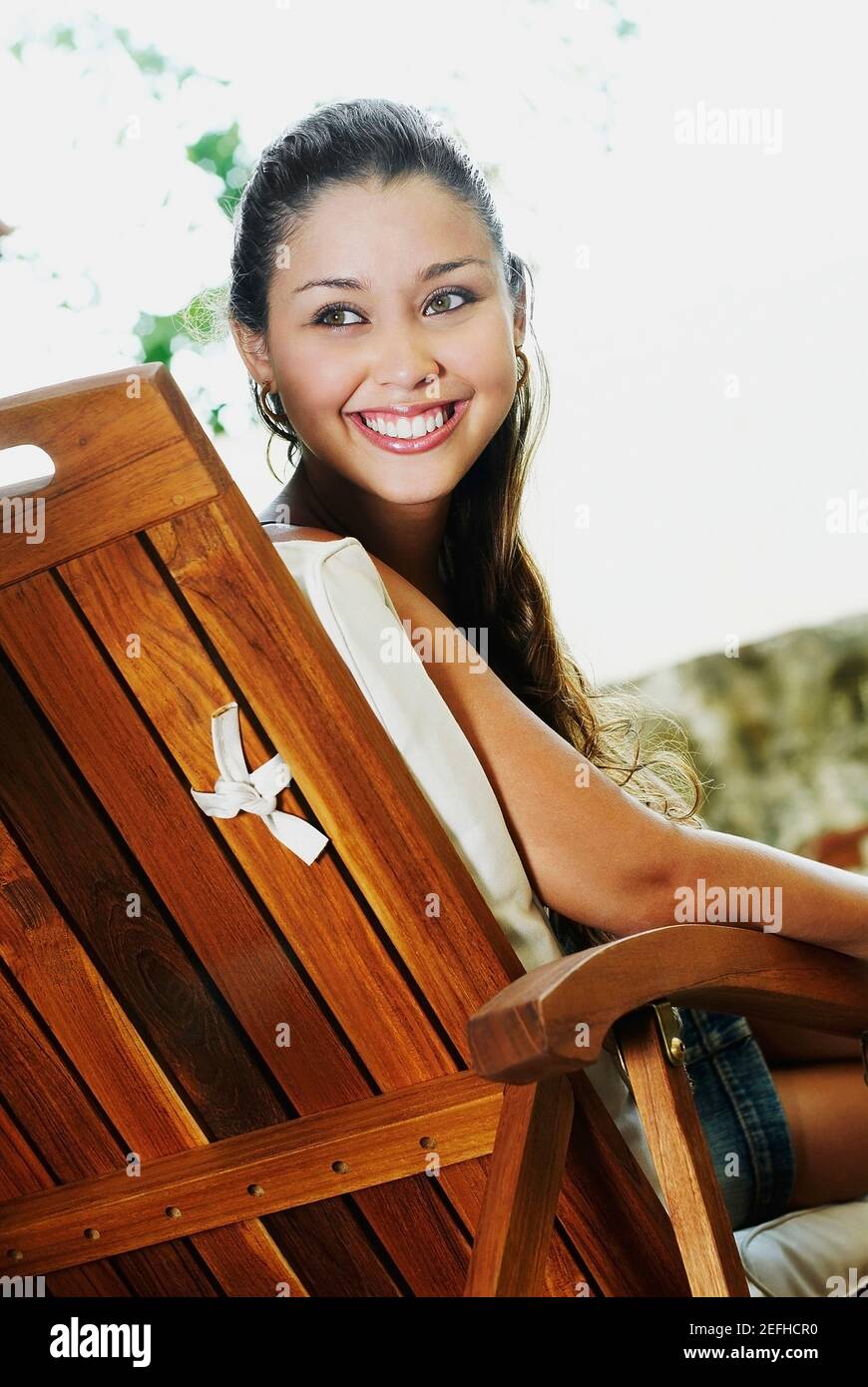 Side profile of a young woman sitting on a lounge chair and smiling ...