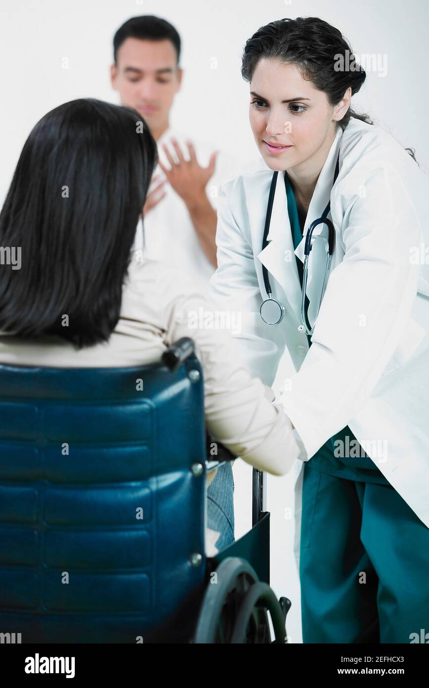 Rear view of female patient sitting on a wheelchair and talking to a ...