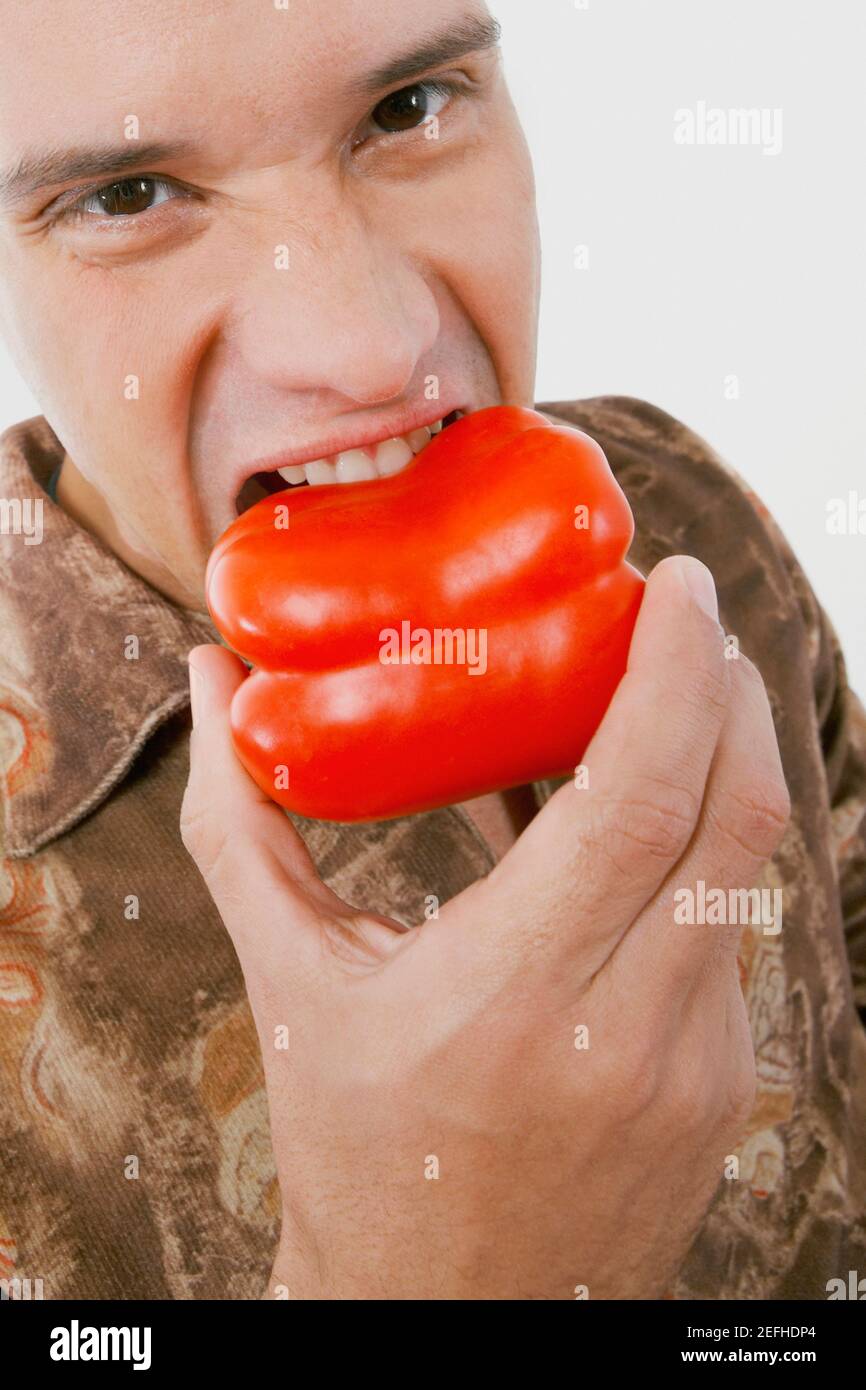 Portrait of a young man eating a red chili pepper Stock Photo - Alamy