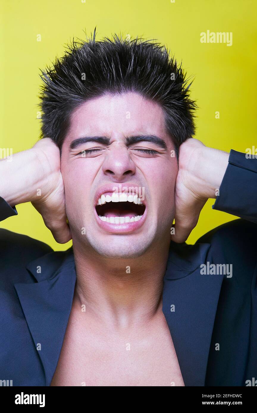 Close up of a young man screaming with his hands on his ears Stock ...
