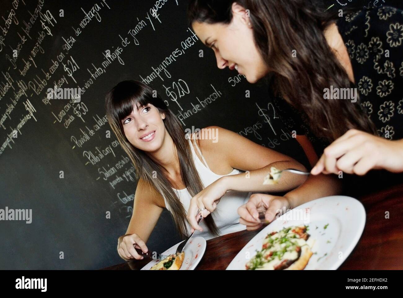 Close up of two young women eating food in a restaurant Stock Photo - Alamy