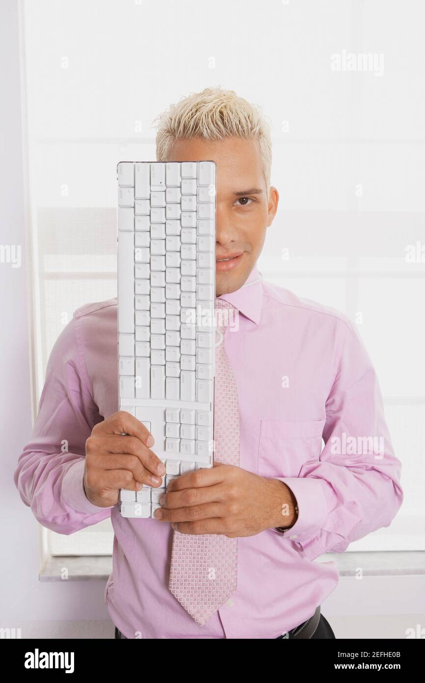 Portrait of a businessman holding a computer keyboard in front of his ...