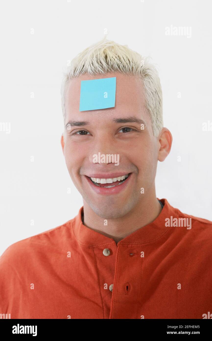 Portrait of a young man smiling with an adhesive note on his forehead ...