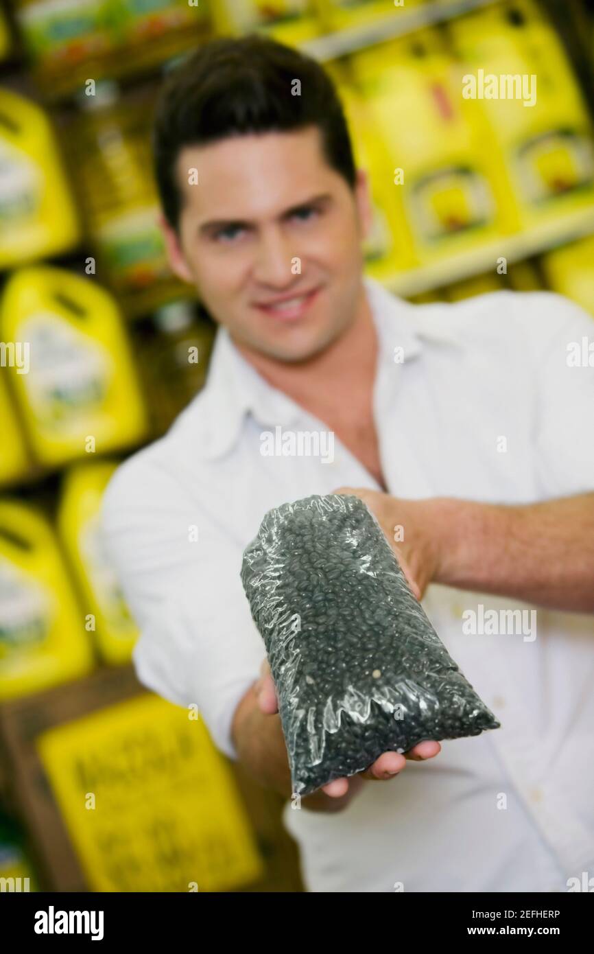 Portrait of a young man holding a packet of pulses in a supermarket ...