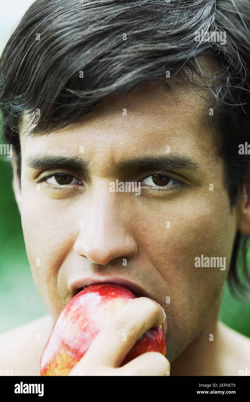 Portrait of a young man eating an apple Stock Photo - Alamy
