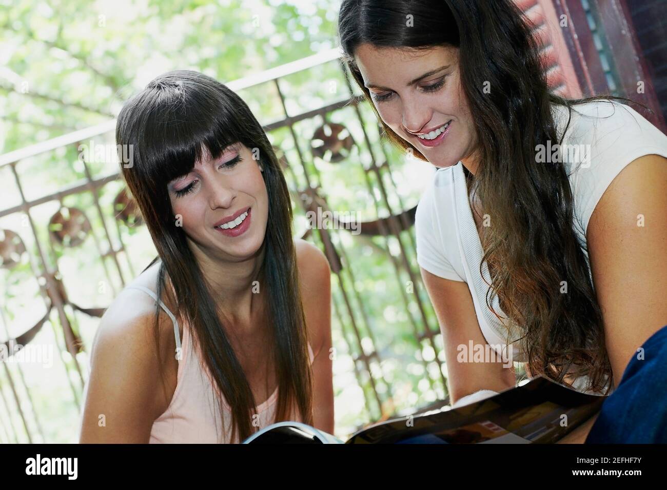 Two young women reading magazine sitting hi-res stock photography and ...