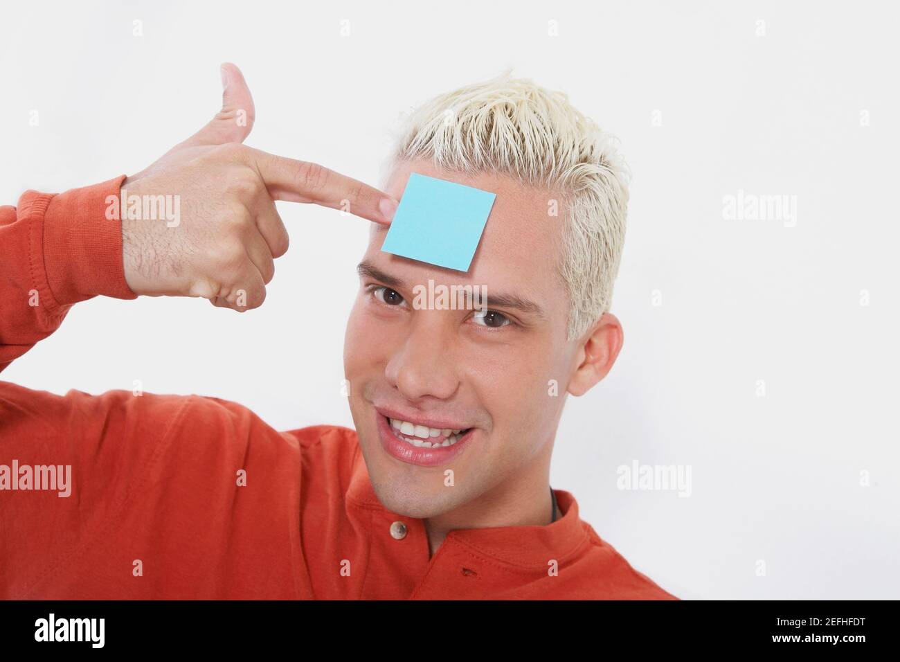 Portrait of a young man smiling with an adhesive note on his forehead ...