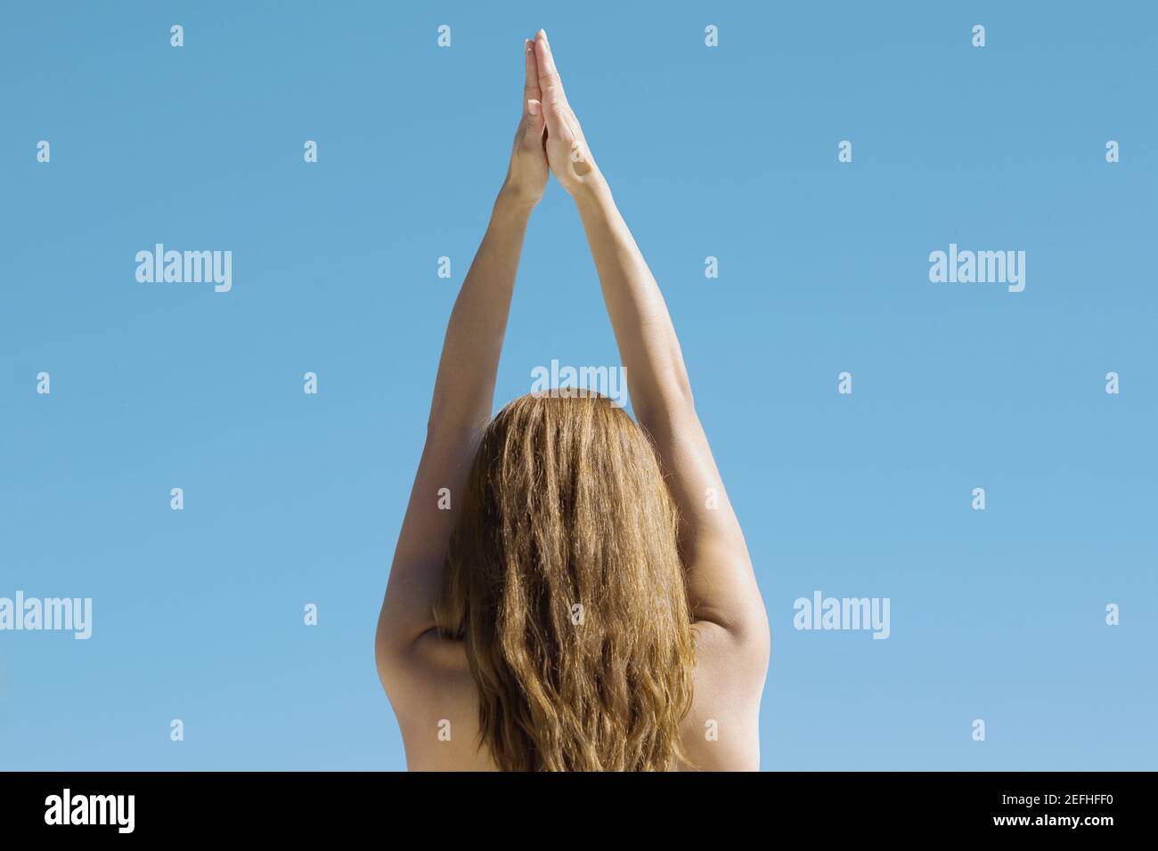 Rear view of a young woman with her arms raised Stock Photo - Alamy