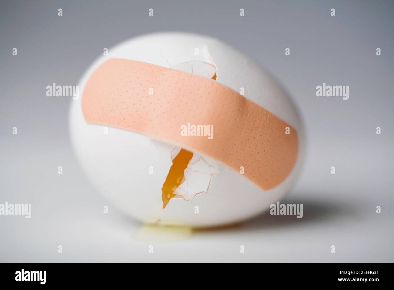 Close up of a broken egg with an adhesive bandage on it Stock Photo - Alamy