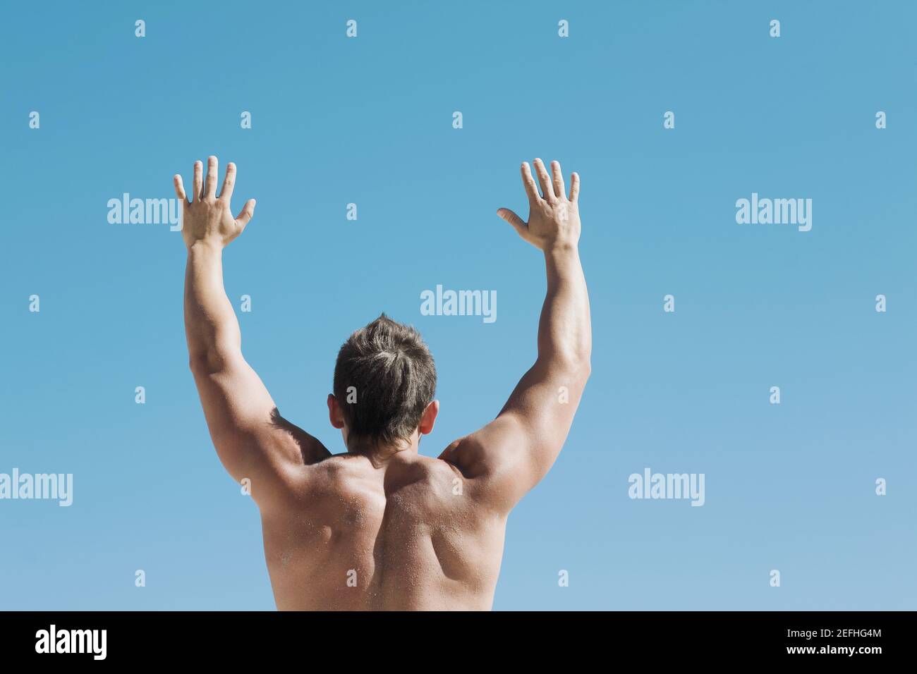 Rear view of a mid adult man standing with his arms raised Stock Photo ...