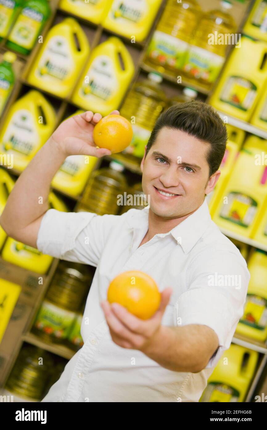 Portrait of a young man throwing an orange in a supermarket Stock Photo ...