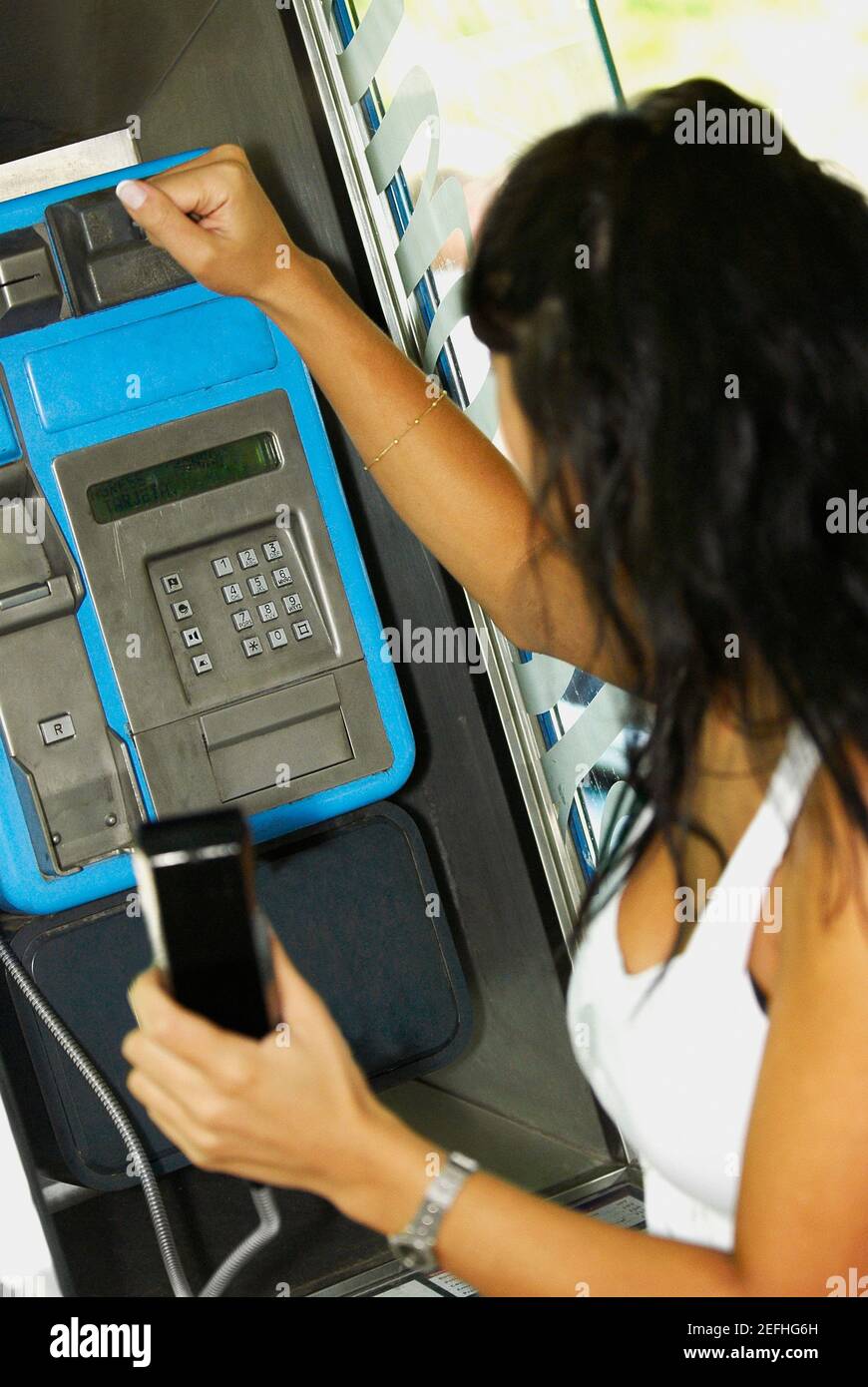 Side profile of a mid adult woman hitting a payphone with her hand ...