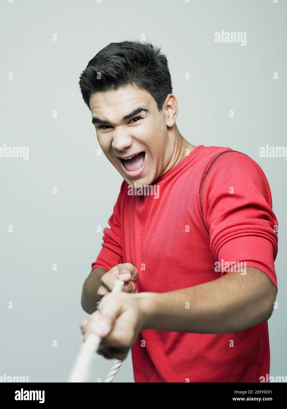 Close up of a young man pulling a rope Stock Photo - Alamy