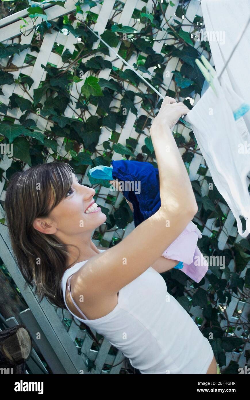 Side profile of a young woman drying clothes on a clothesline Stock ...