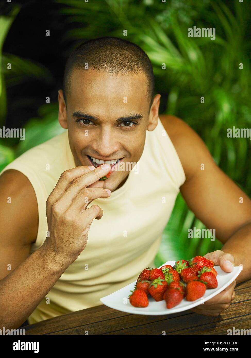 Portrait of a young man eating a strawberry Stock Photo - Alamy
