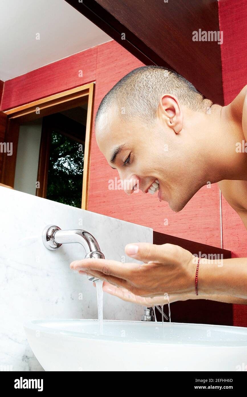 Side profile of a young man washing his face in the bathroom sink Stock Photo - Alamy