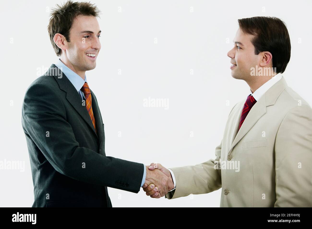 Side profile of two businessmen shaking hands and smiling Stock Photo ...