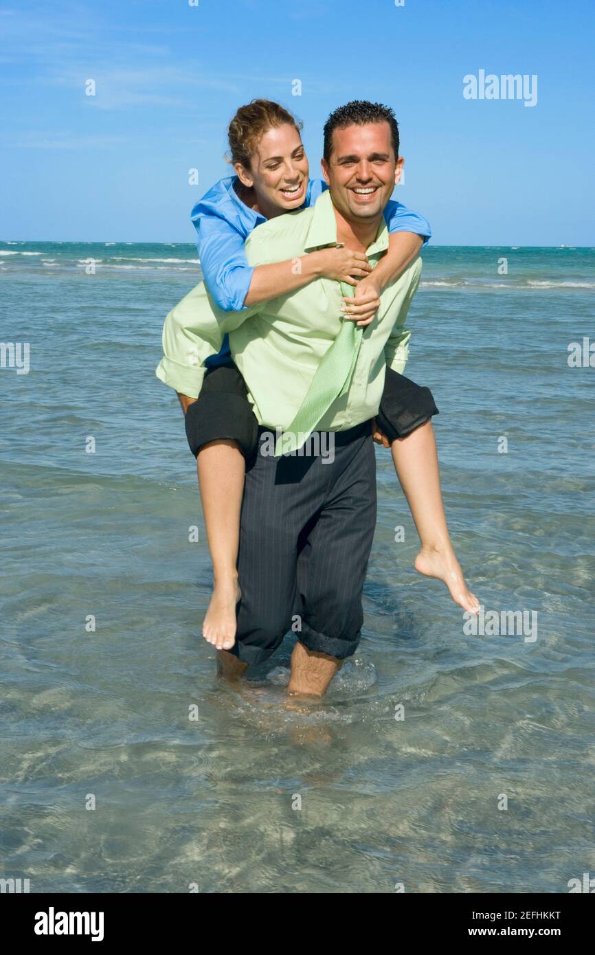 Mid adult woman riding piggyback on a mid adult man on the beach Stock ...