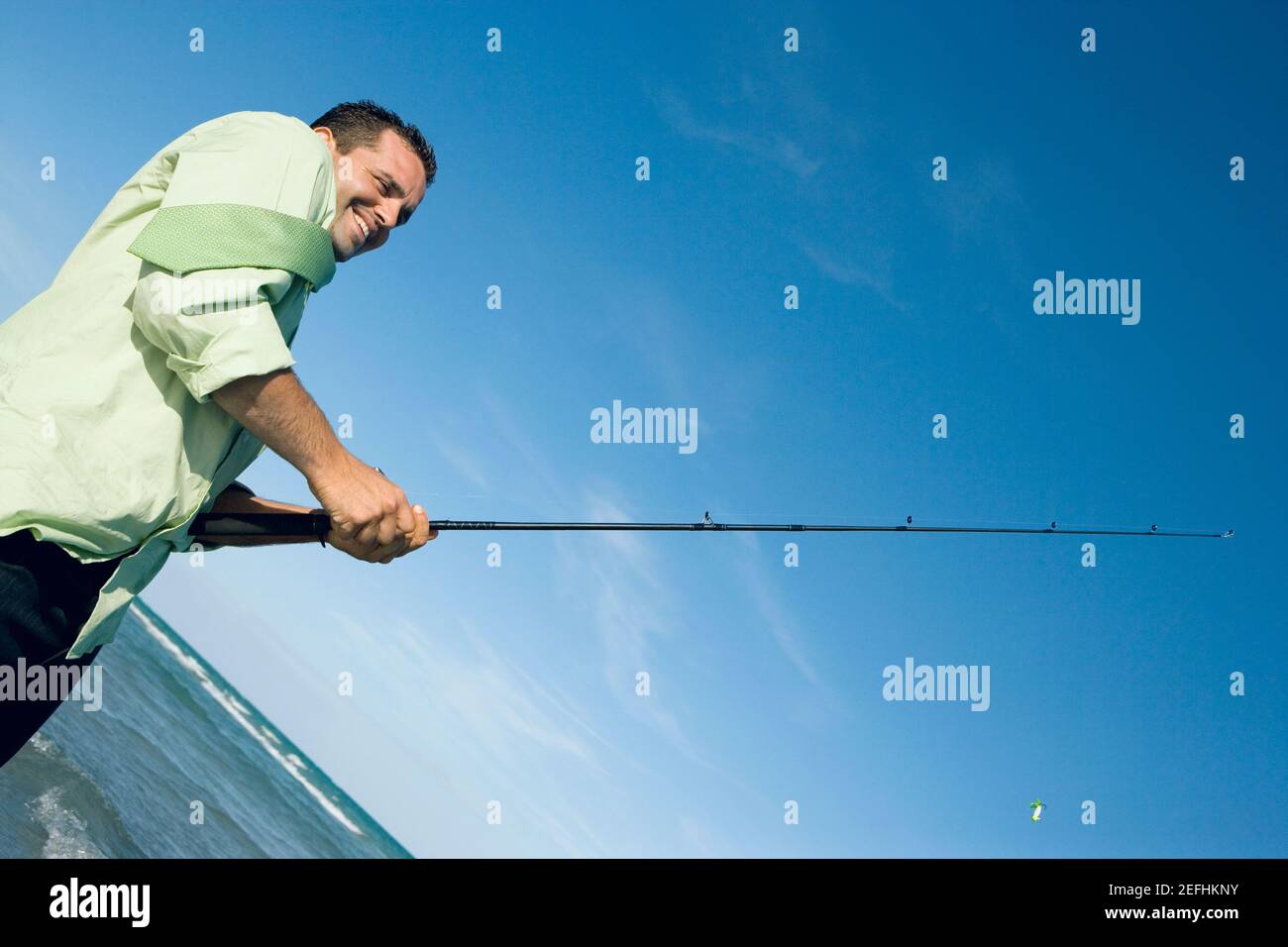 Side profile of a mid adult man holding a fishing rod on the beach ...