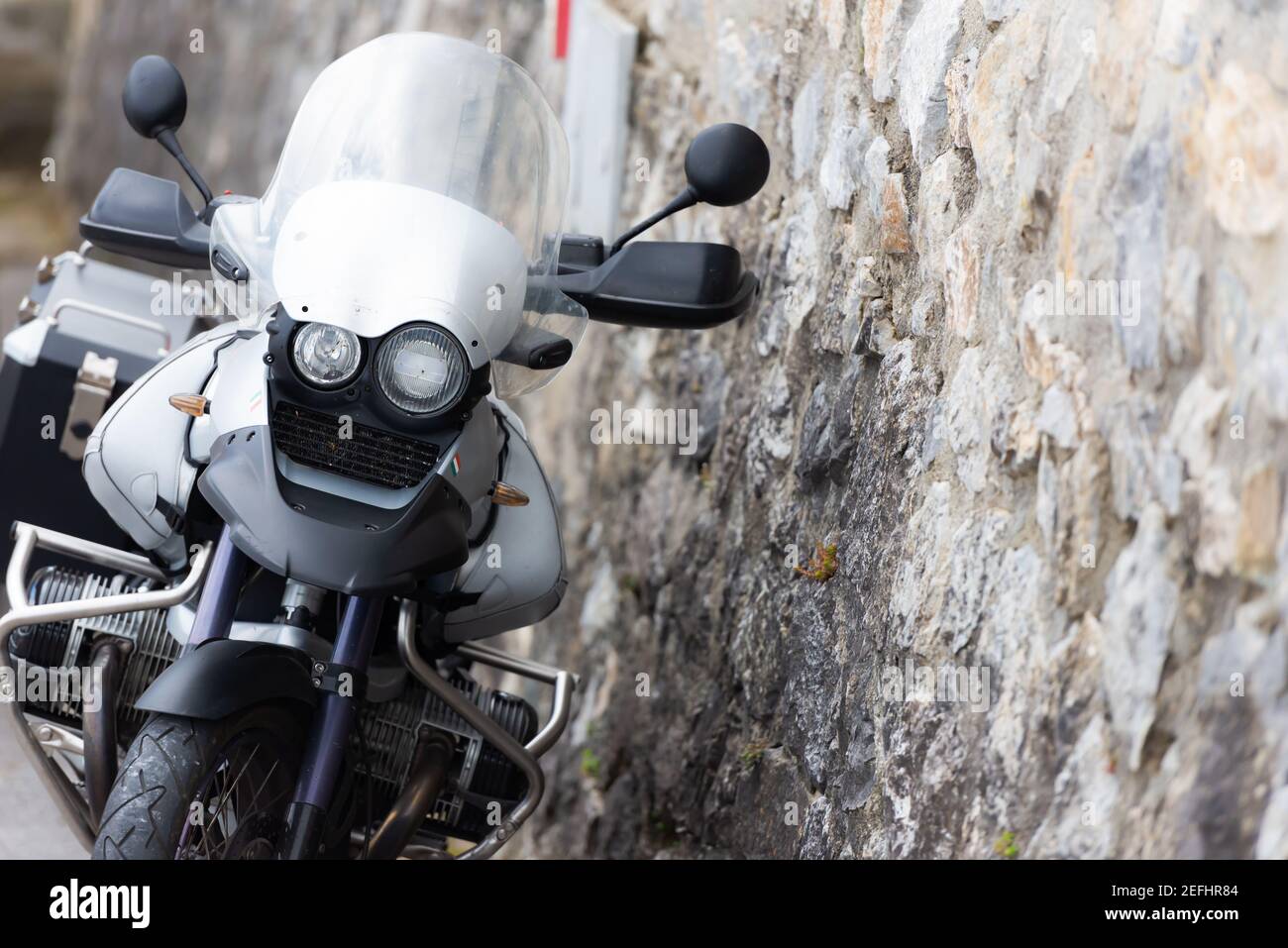 Off-road motorcycle at the stone wall. A gray motorcycle is leaning ...
