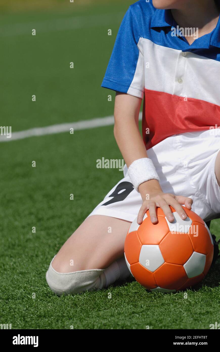 Mid section view of a soccer player kneeling on a soccer field with a ...