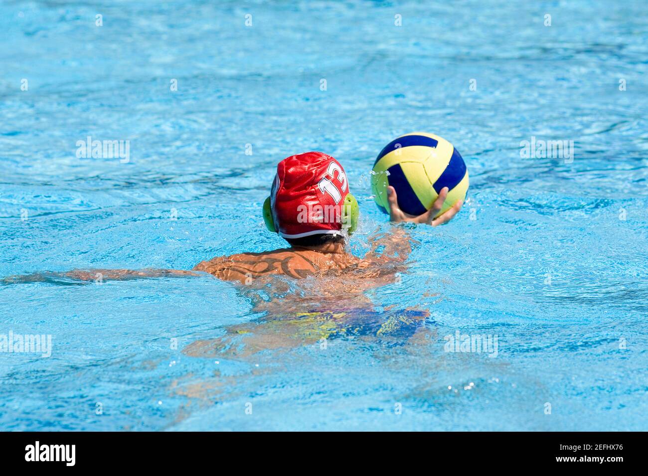 Rear view of a man playing water polo in a swimming pool Stock Photo ...