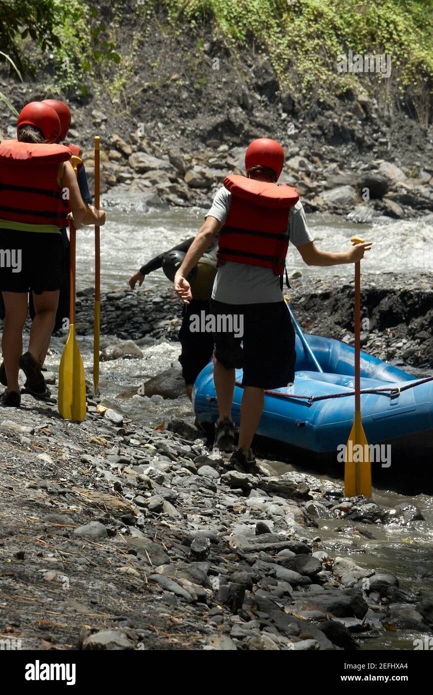 Four people walking towards an inflatable raft at a riverside Stock ...