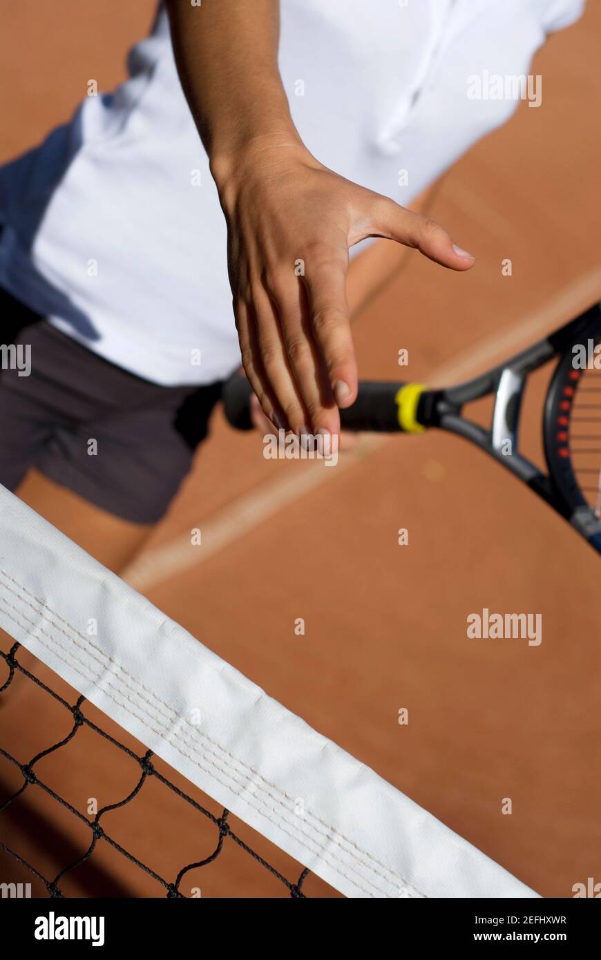 Mid section view of a young woman holding a tennis racket and reaching ...