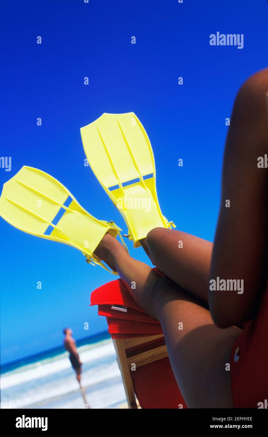 Close-up of a woman sitting on the beach wearing flippers, Caribbean ...