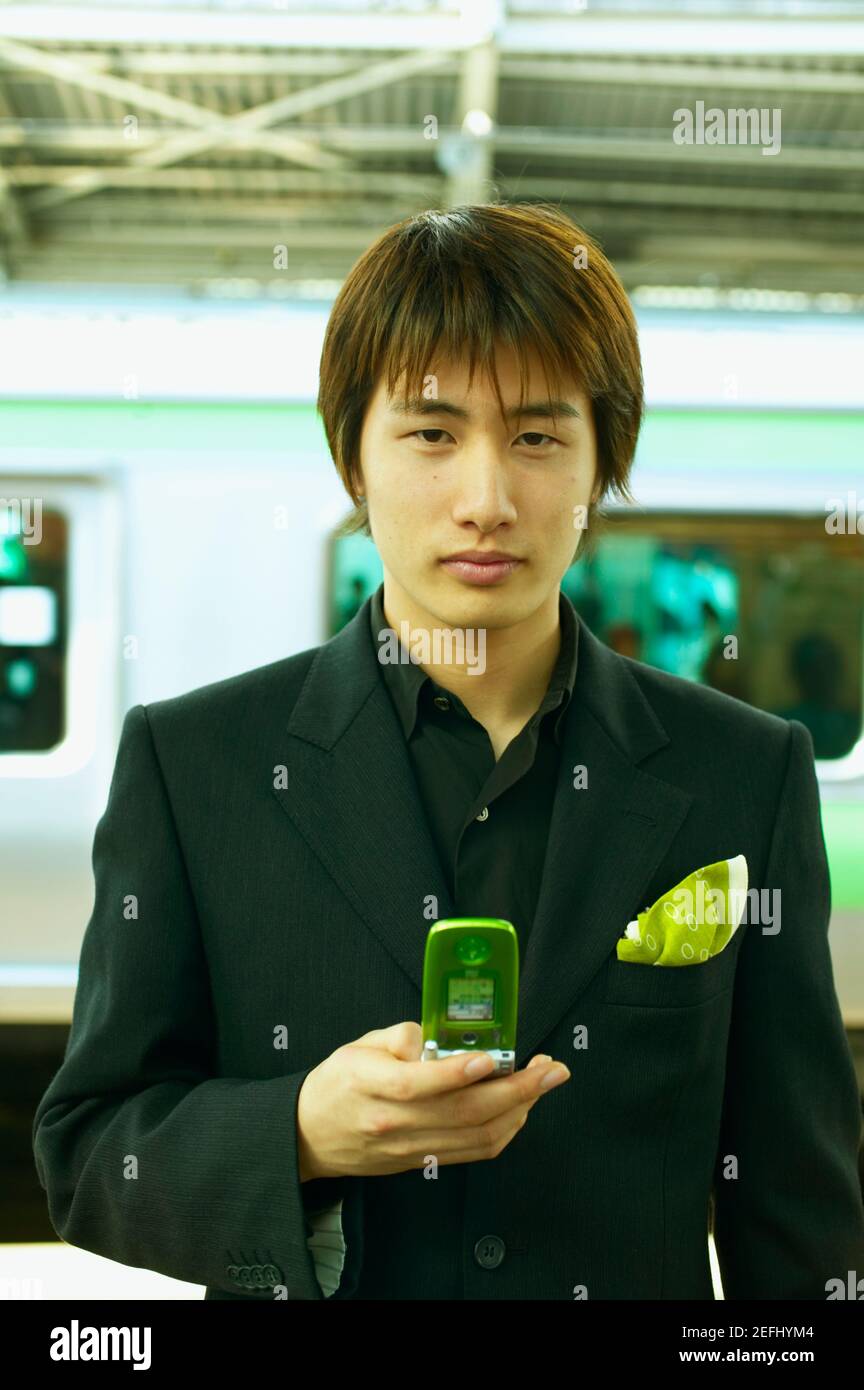 Portrait of a young man holding a mobile phone Stock Photo - Alamy