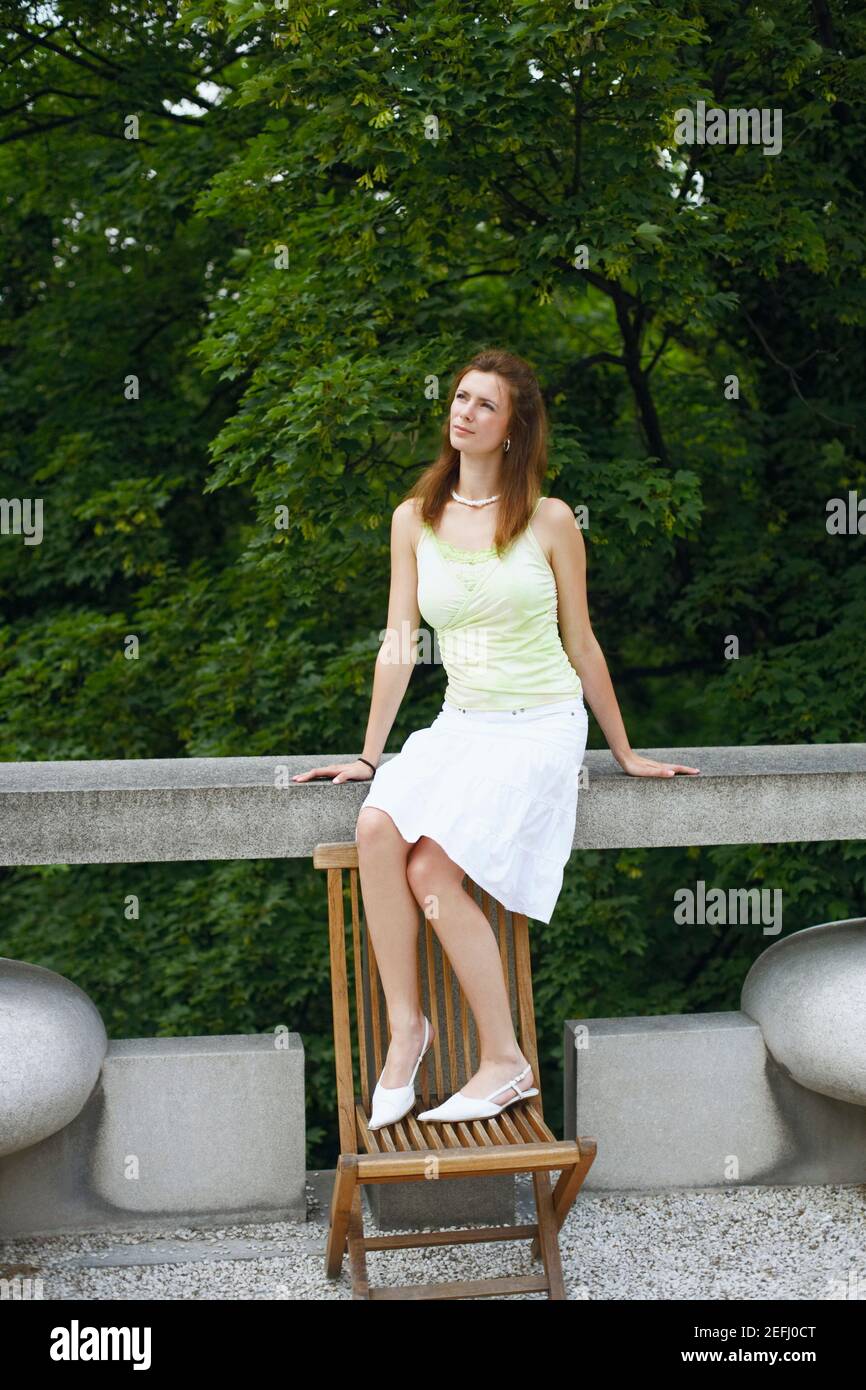 Young woman sitting on a railing Stock Photo - Alamy