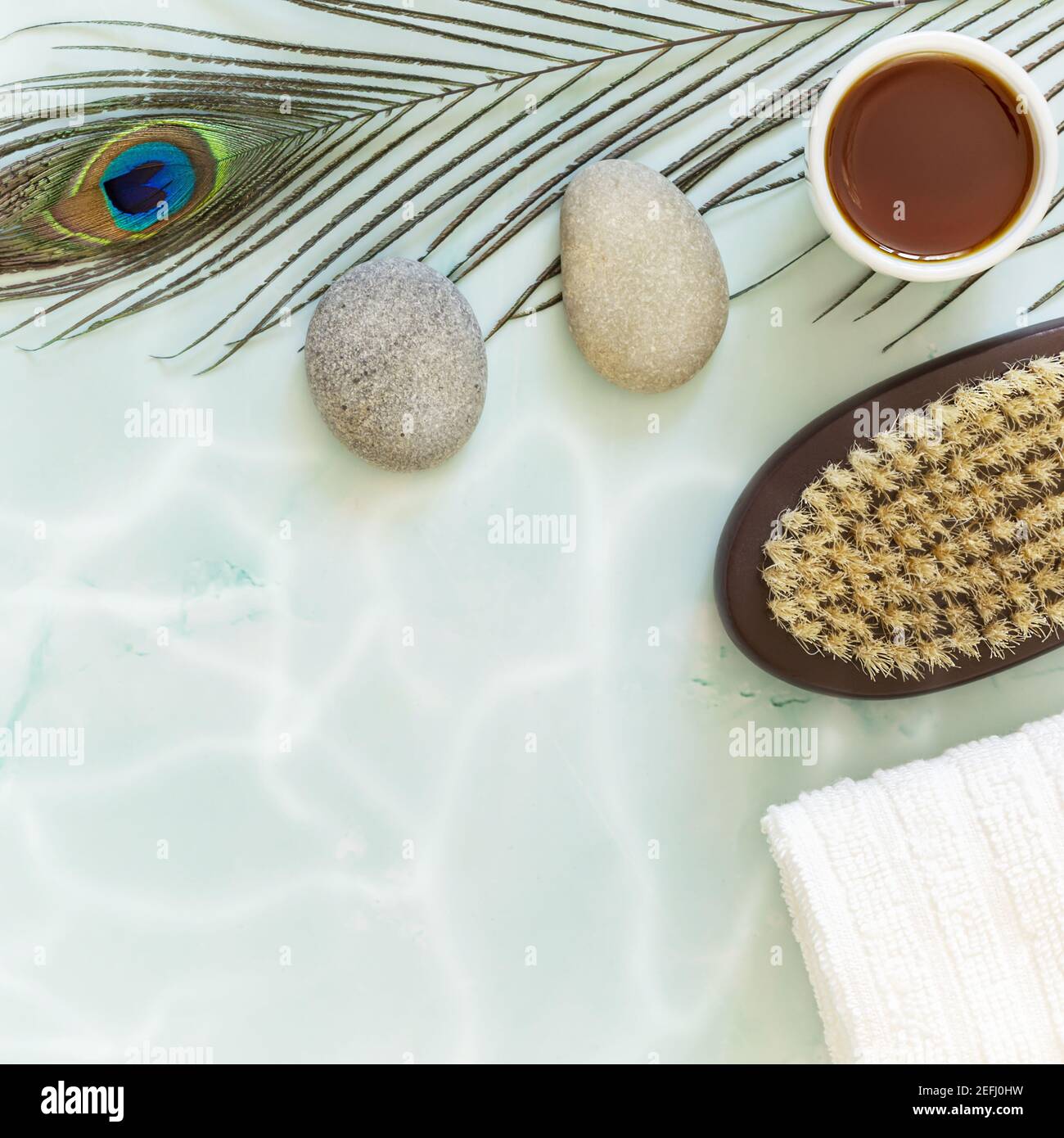 Flat lay composition with peacock feather, massage stones, oil, body ...