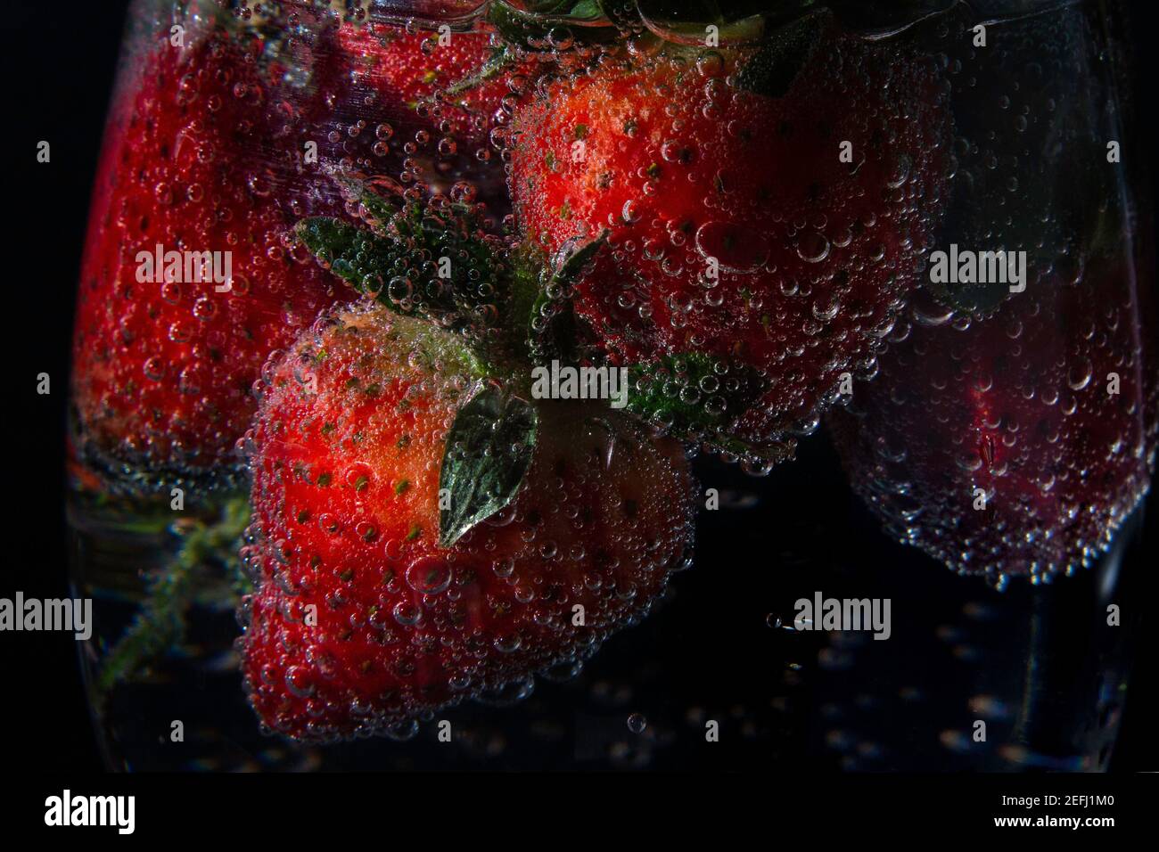 Strawberries submerged in fizzy liquid on a black background Stock ...