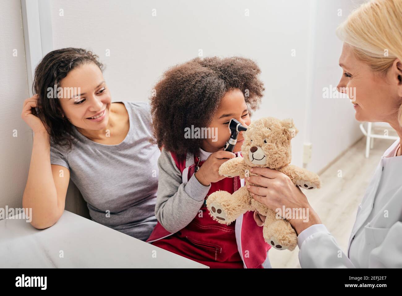ENT doctor checking African female kid's ear using an otoscope. Hearing ...