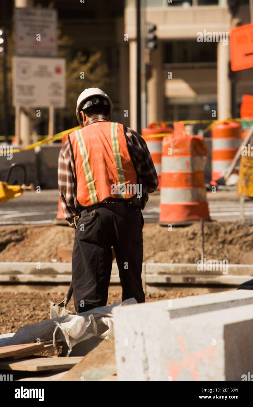 Rear view of a construction worker standing at a construction site ...