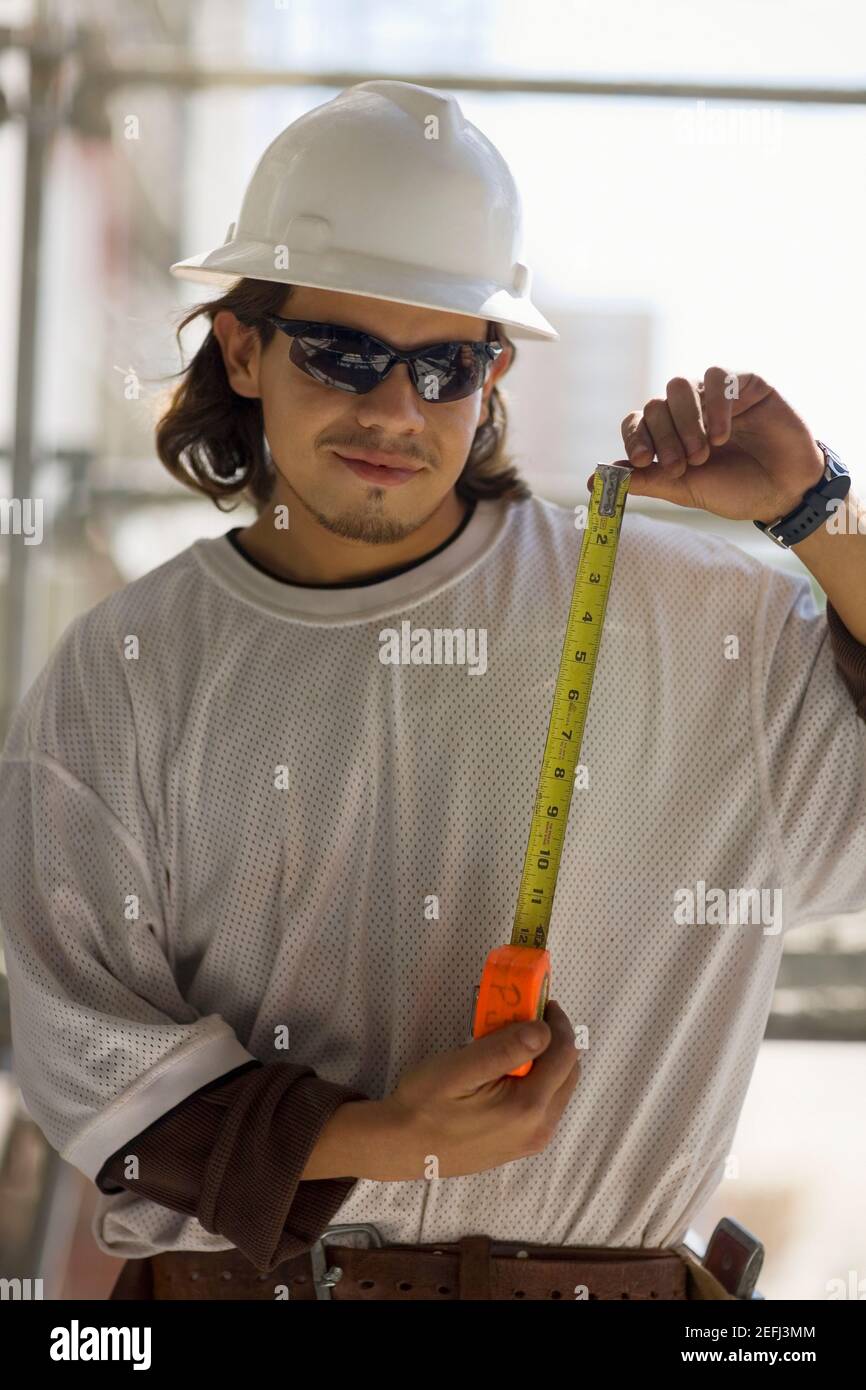 Young man holding a tape measure Stock Photo - Alamy