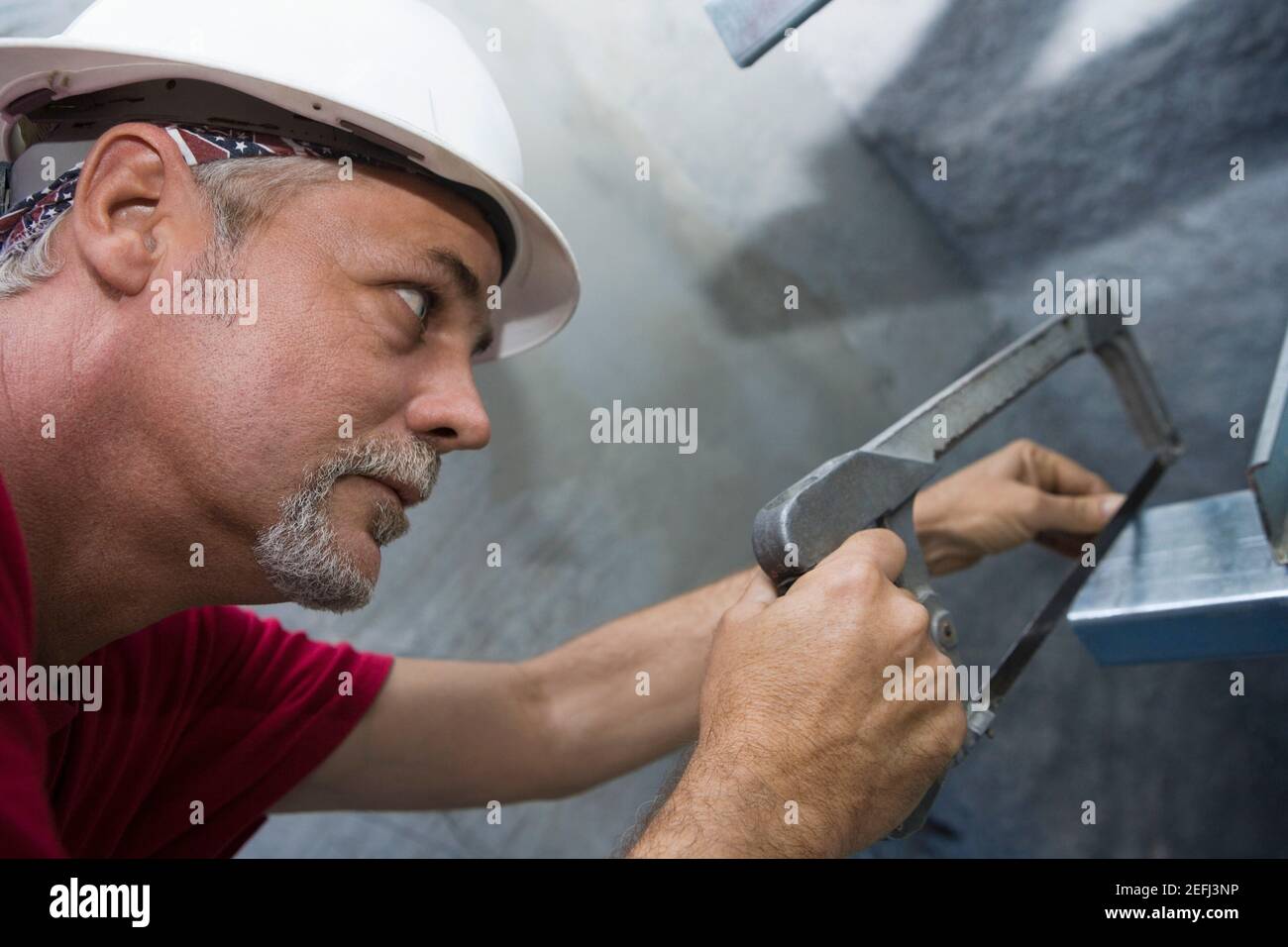 Close-up of a male construction worker cutting a metal sheet with a saw ...