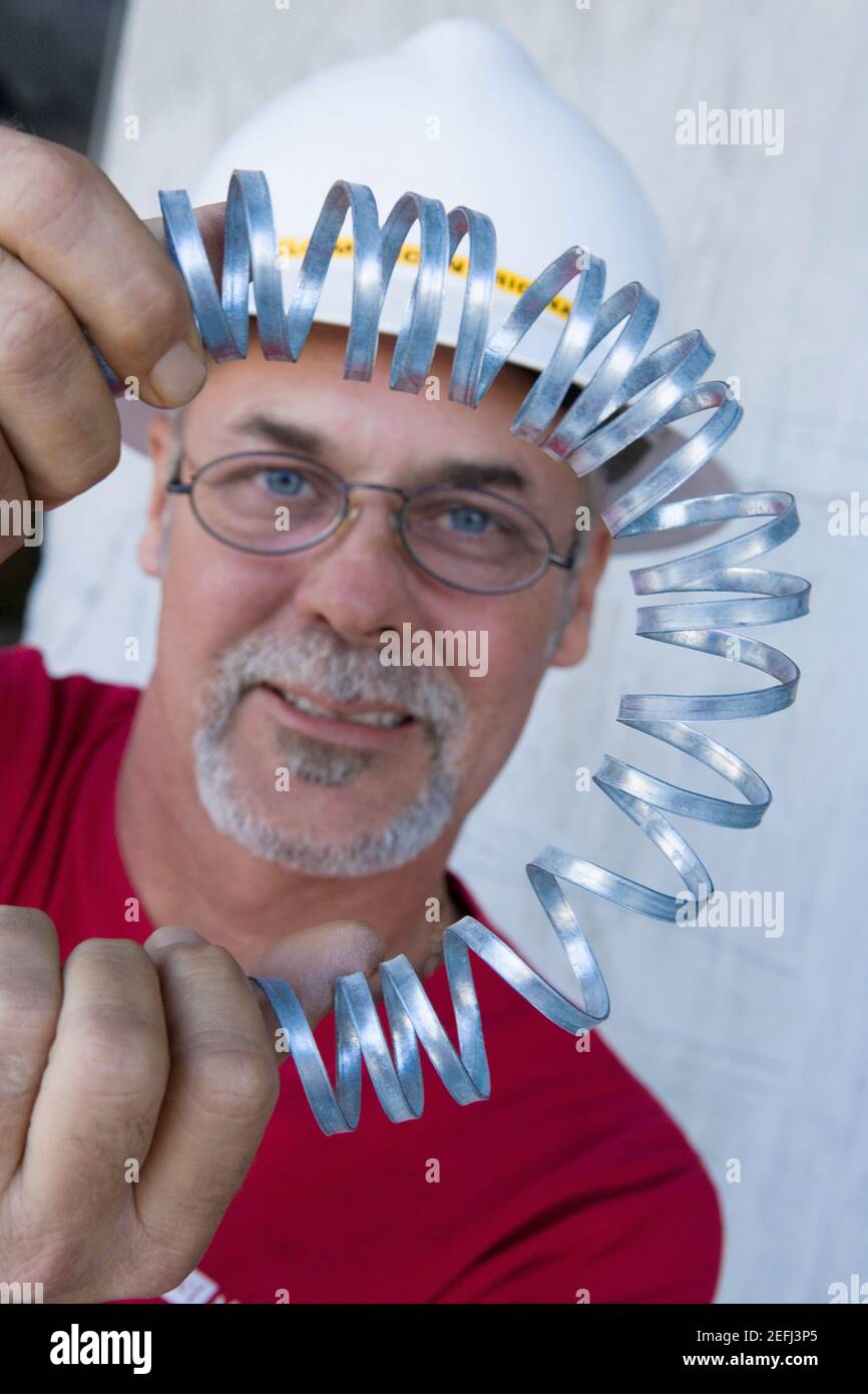 Portrait of a male construction worker folding a metal spring and ...