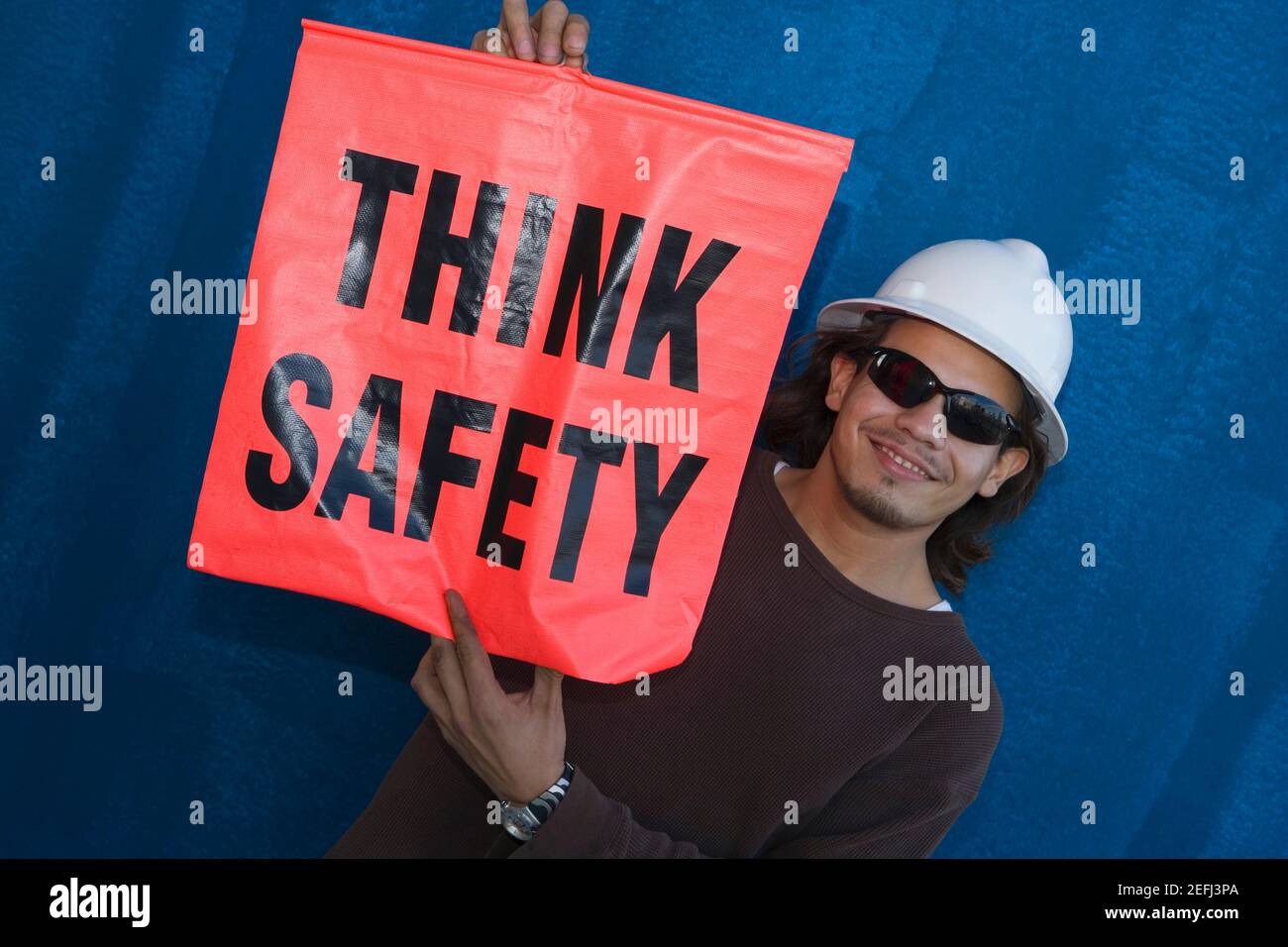 Close-up of a male construction worker smiling and holding a warning ...