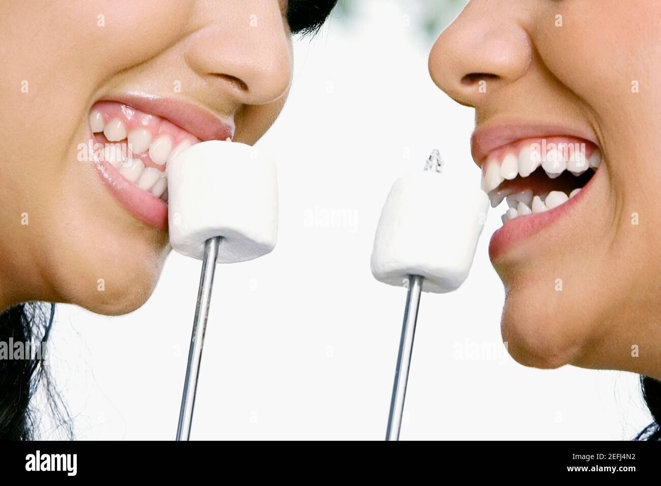 Close-up of two young women eating marshmallows Stock Photo - Alamy