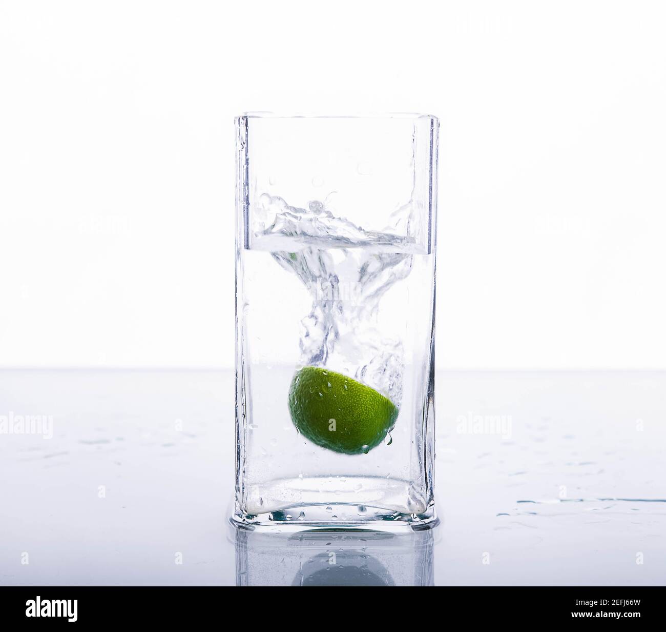 Lime splashing into glass of water on white background Stock Photo - Alamy