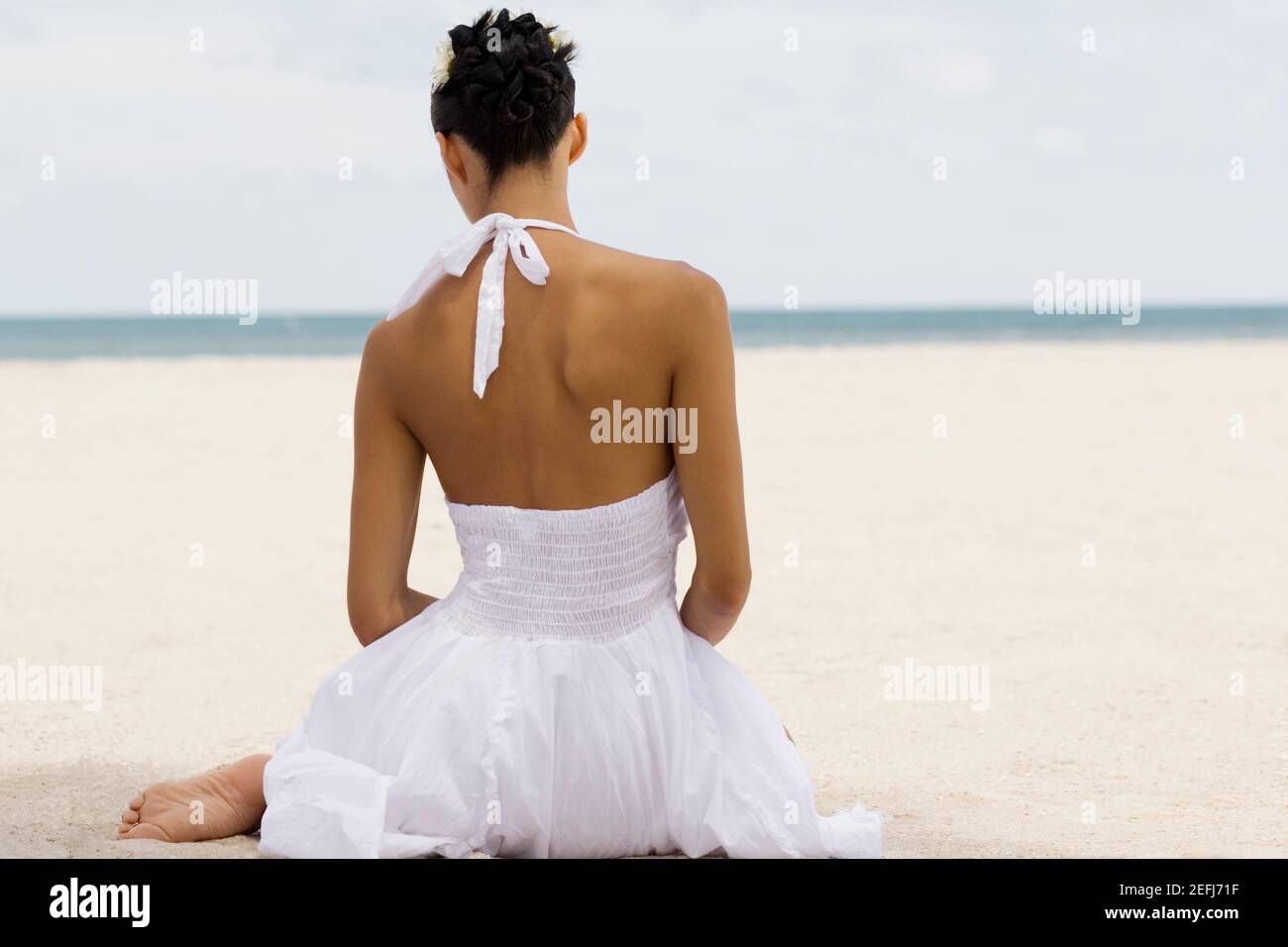 Rear view of a young woman sitting on the beach Stock Photo - Alamy
