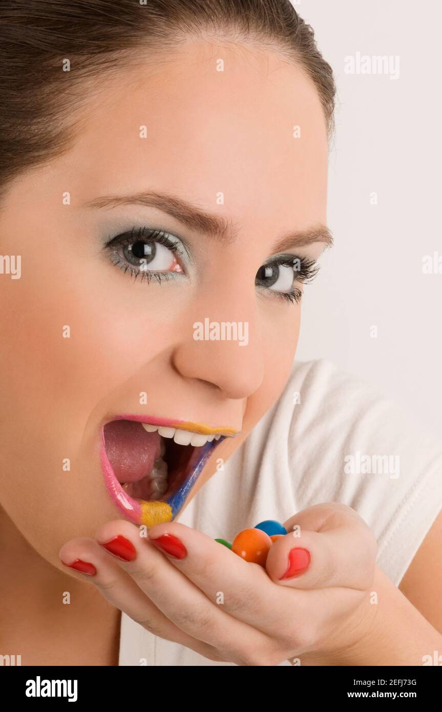 Portrait of a young woman eating candies Stock Photo - Alamy