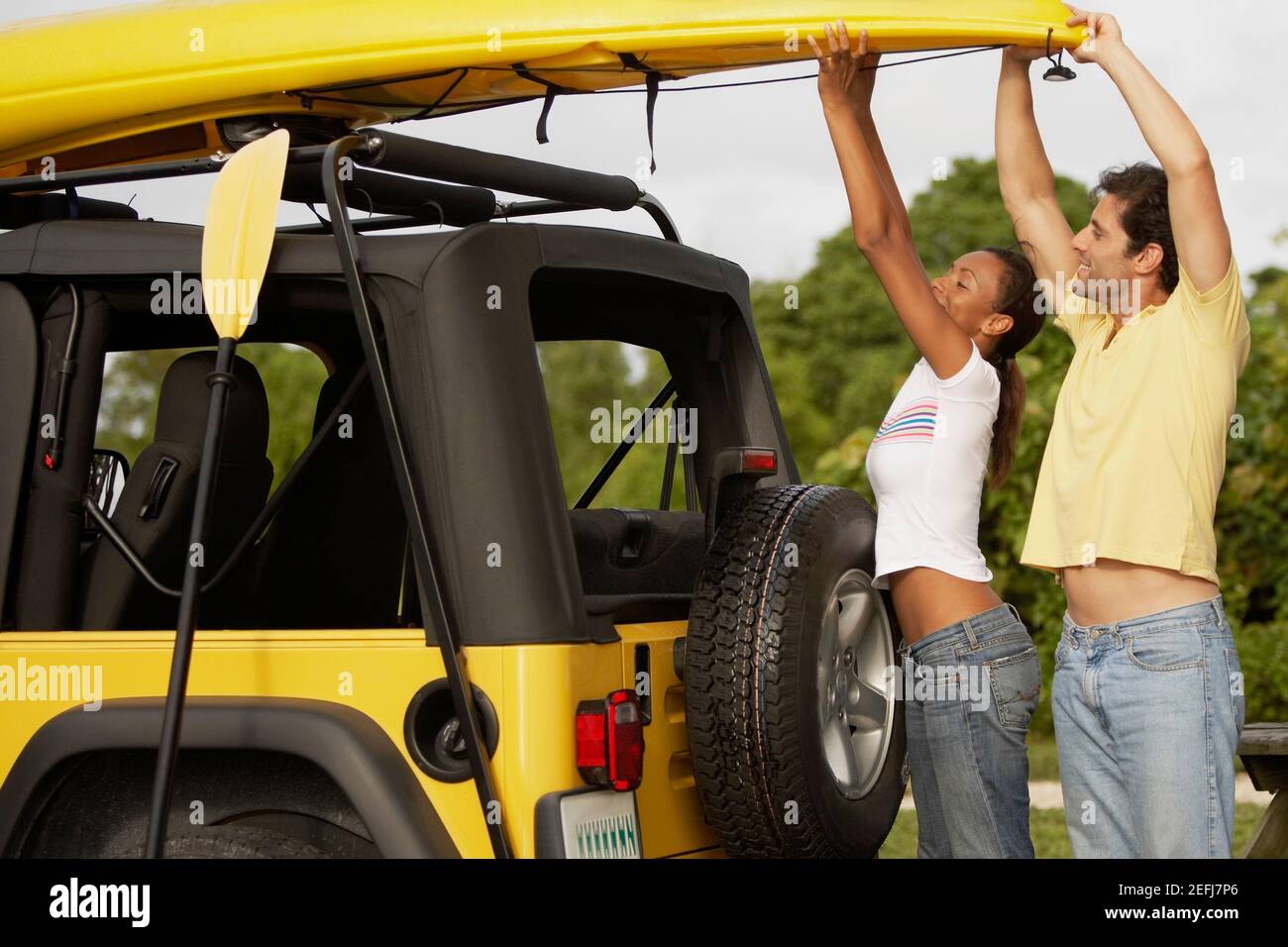 Side profile of a mid adult man and a young woman taking a kayak from ...
