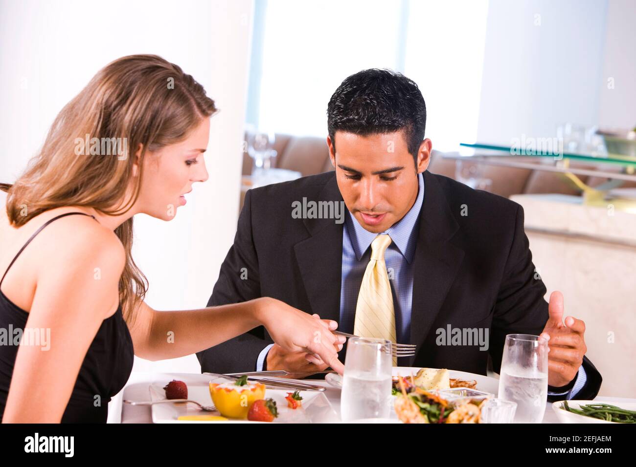 Side profile of a young woman and a mid adult man eating in a ...
