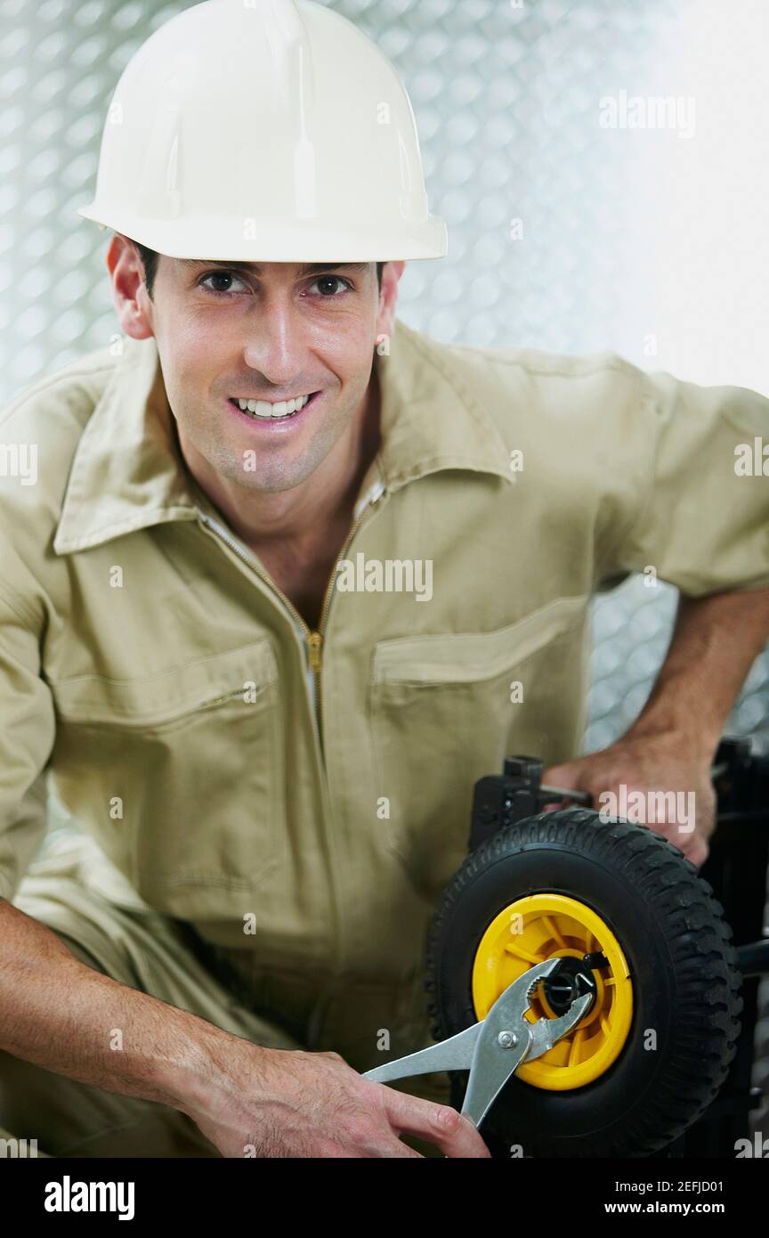 Portrait of a mid adult man tightening a nut of a wheel Stock Photo - Alamy