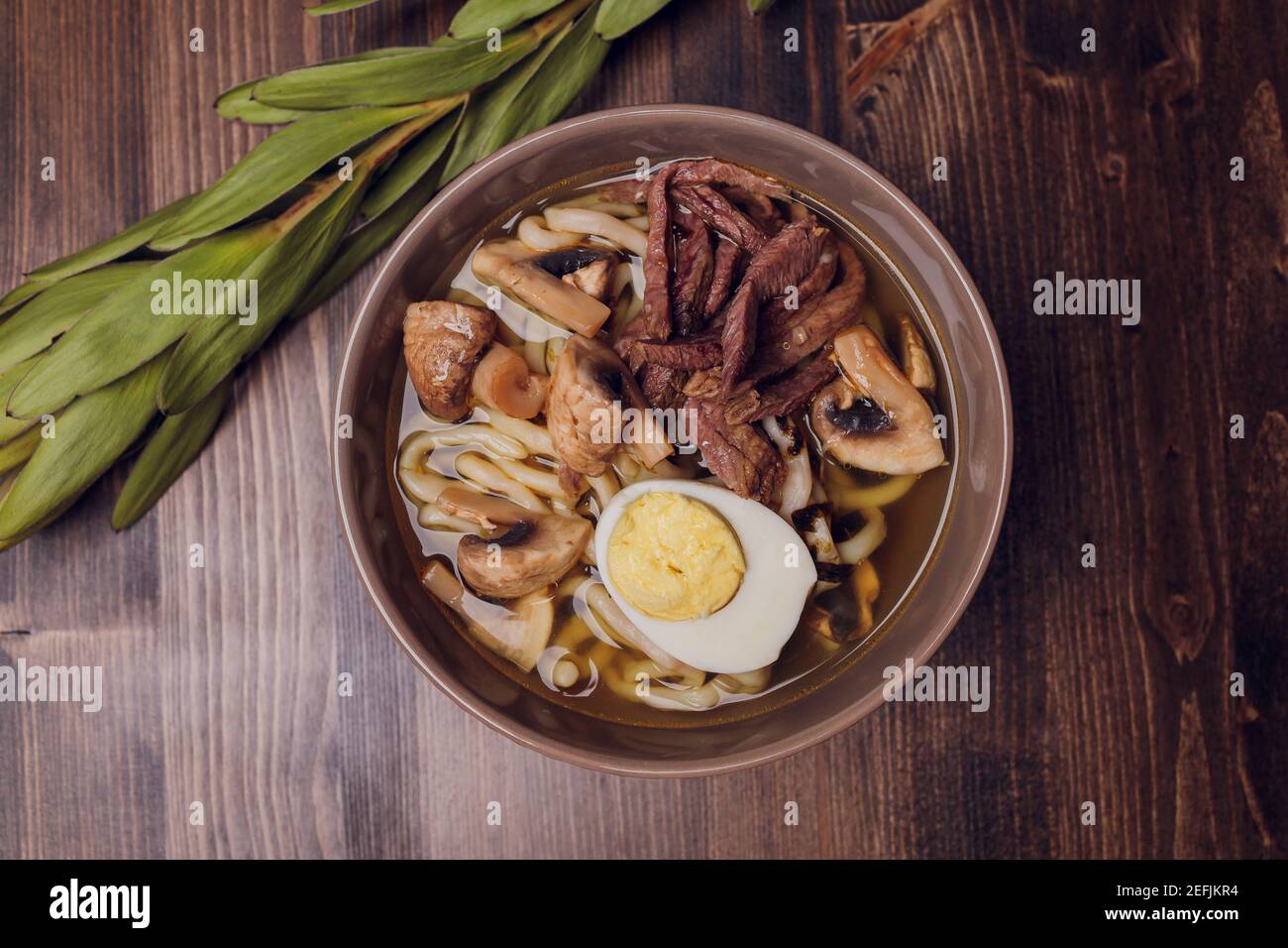 Ramen noodles soup on a wooden cutting board with freshly cut onions ...