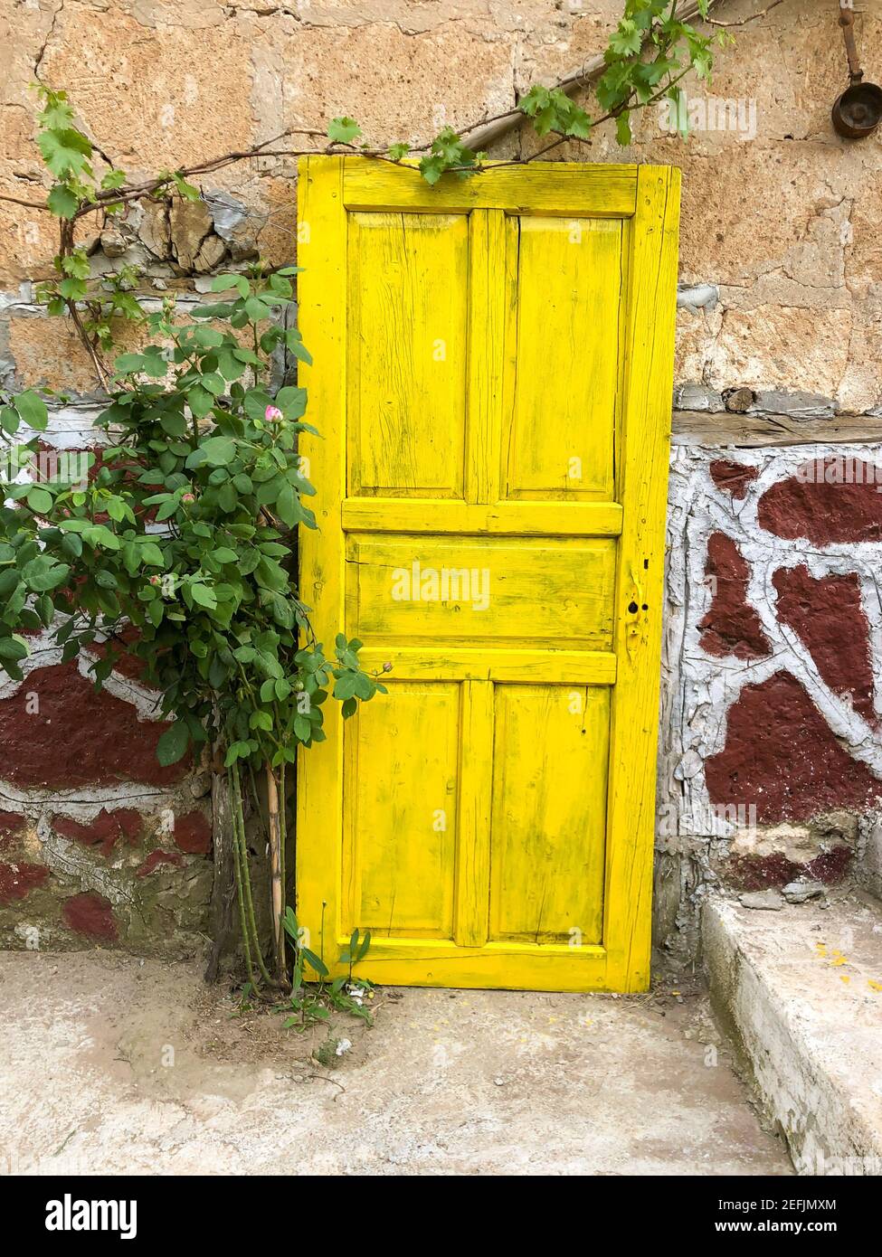 a yellow painted wooden door on the wall of an old house Stock Photo ...